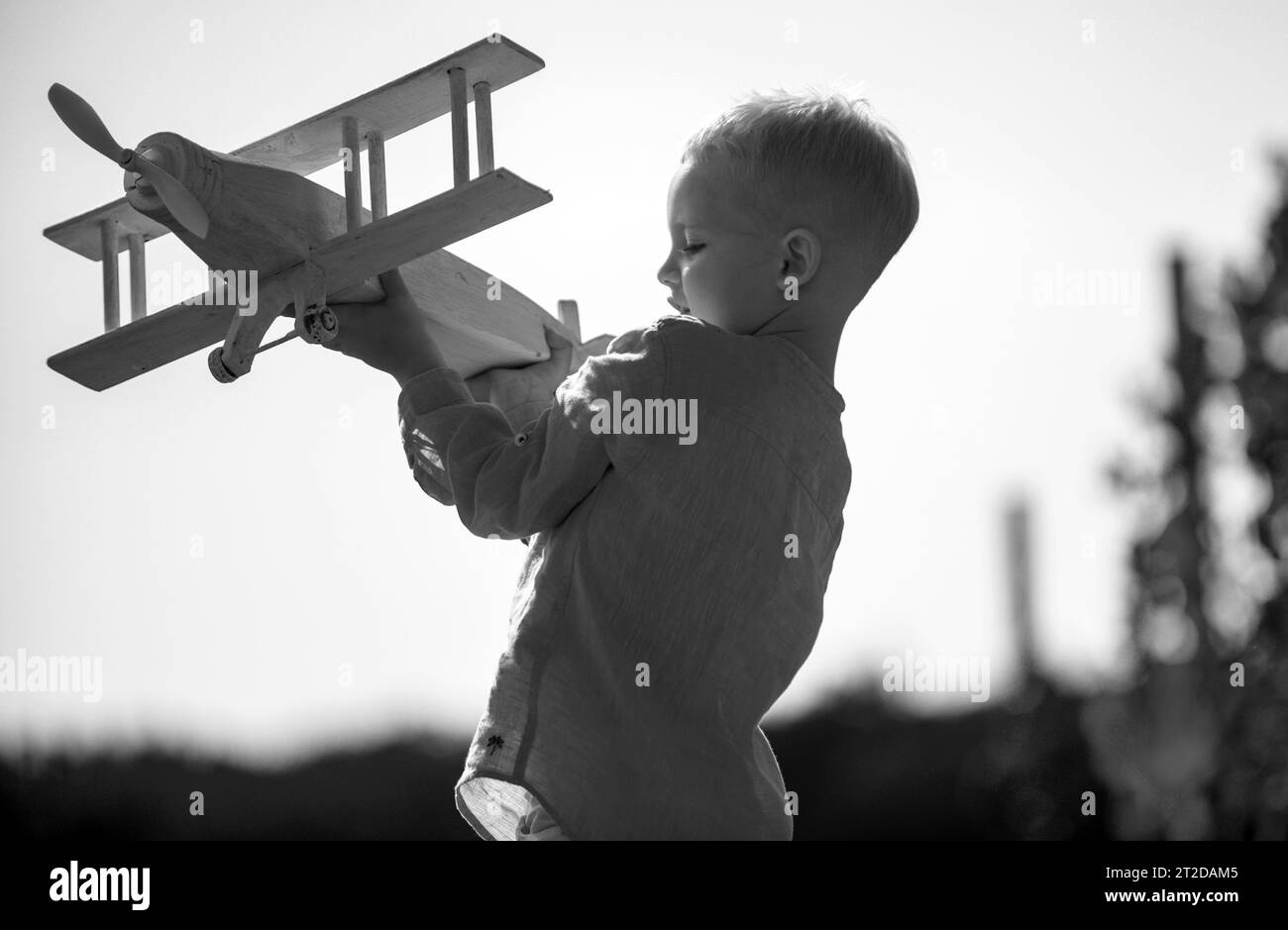 Child pilot with toy airplane dreams of traveling in summer in nature ...