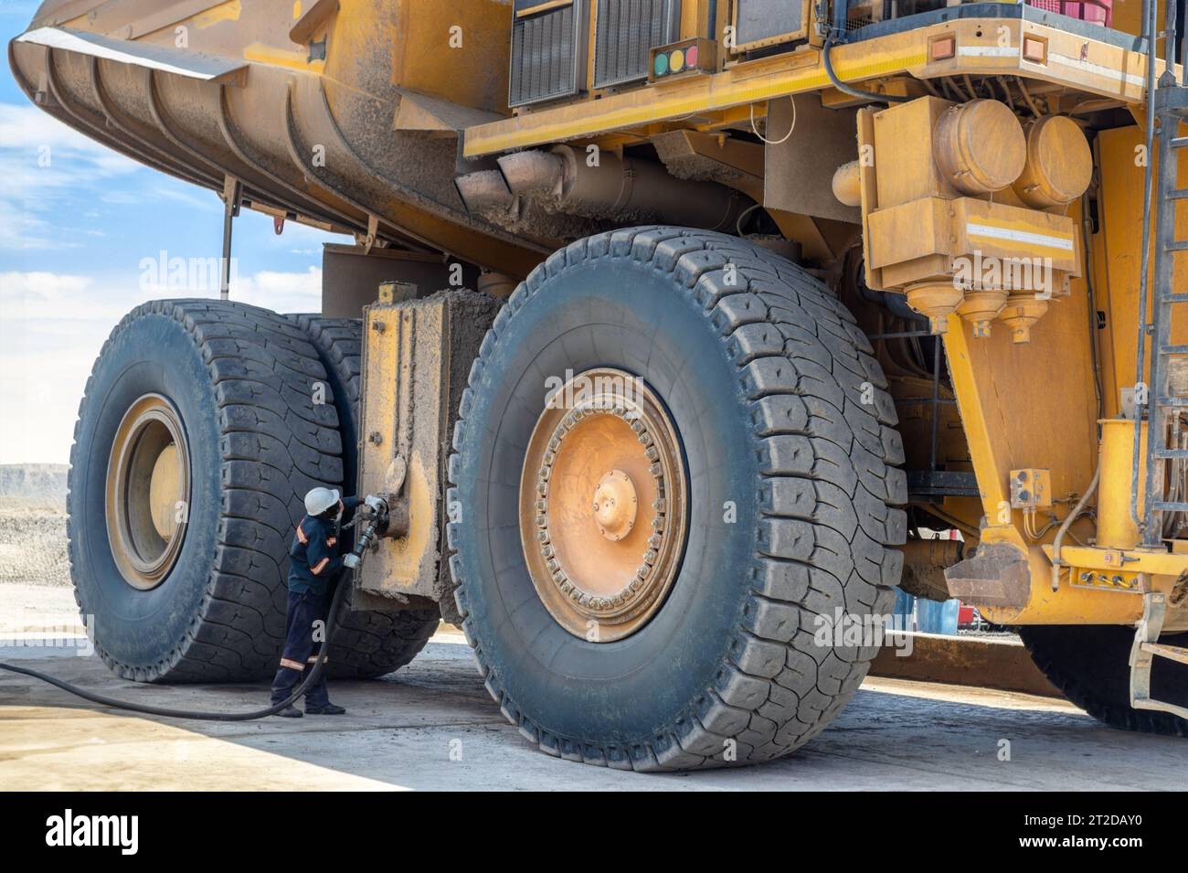 open pit diamond mine, worker at the fuel pump refuel huge truck with ...