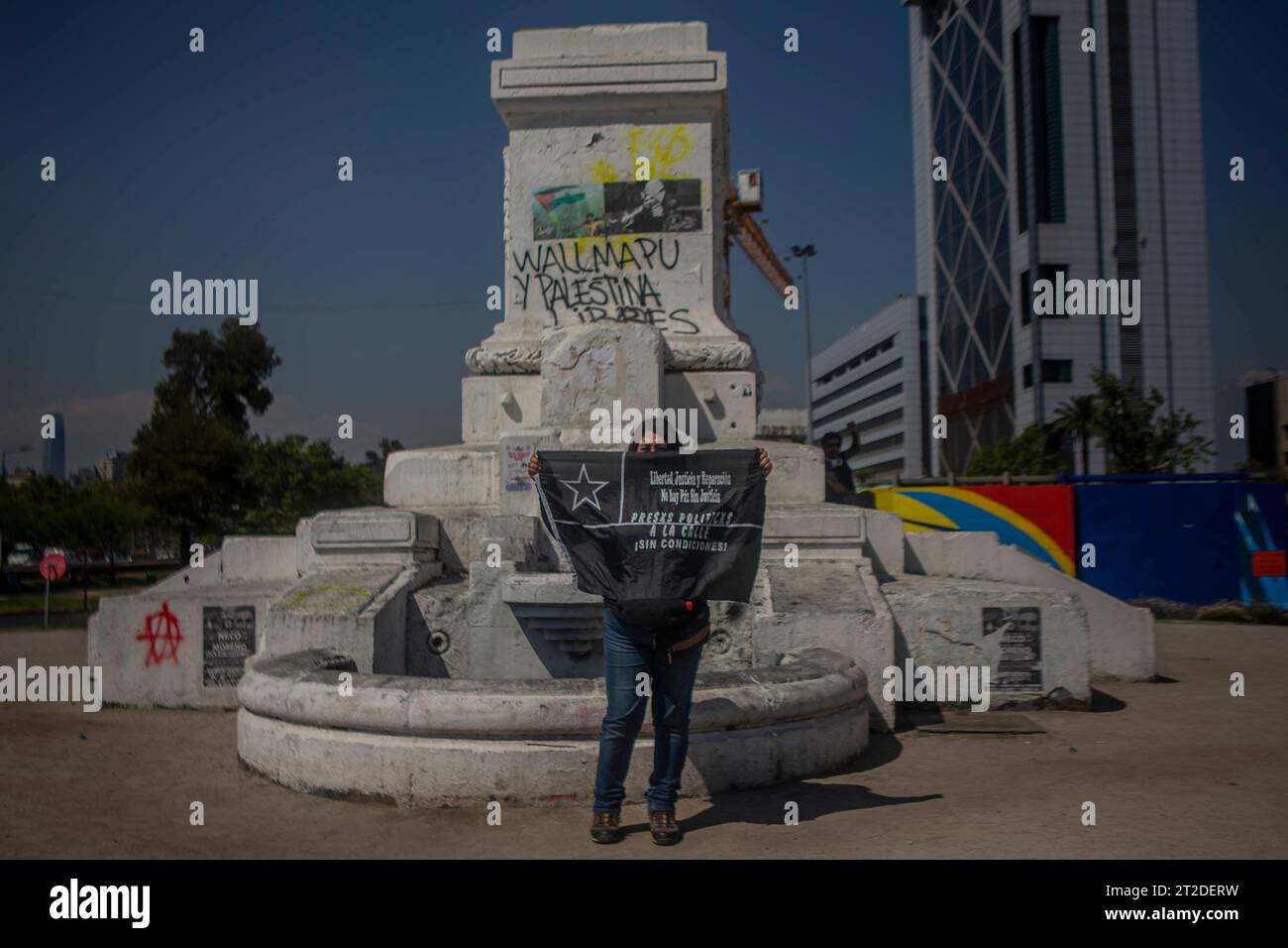 A woman holds a black Chilean flag standing in front of the base of the ...