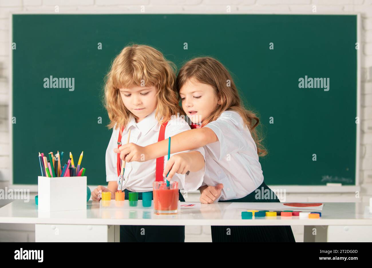 School children drawing a colorful pictures with pencil crayons in ...