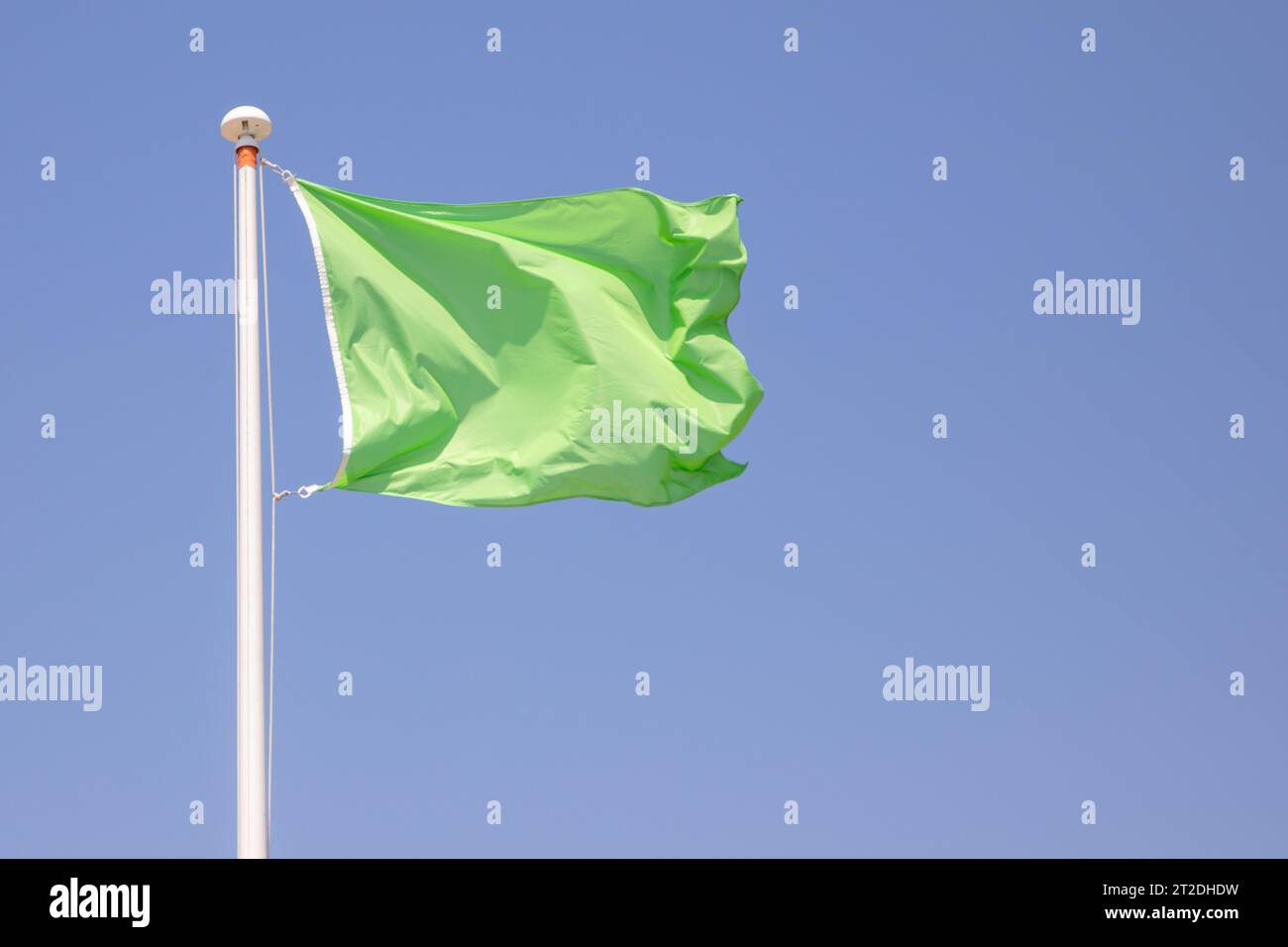 Green flag sign on the beach over bright blue sea safety signs at ...