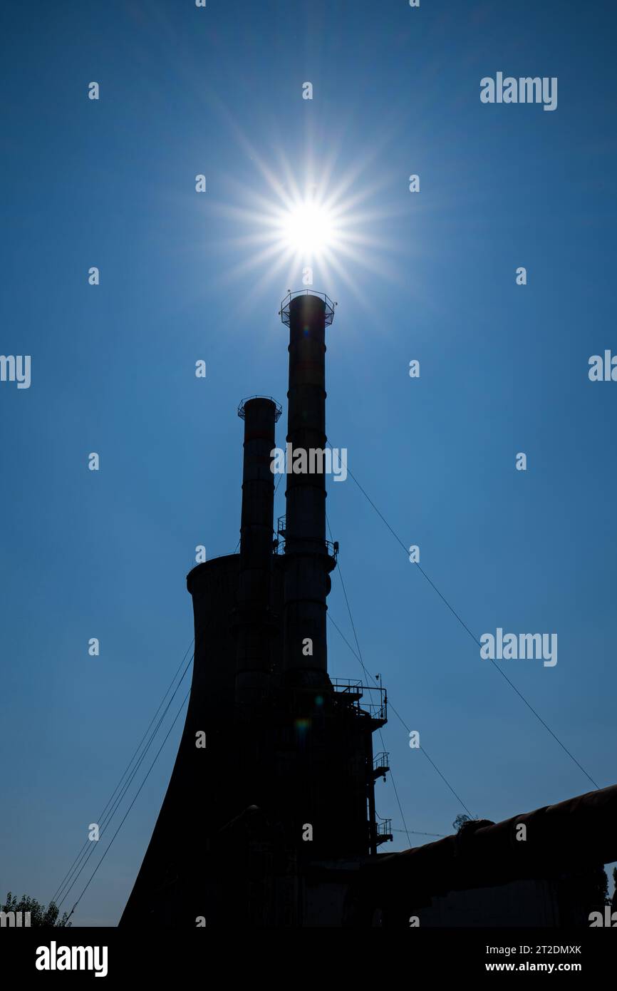 Industrial chimney or smoke stacks silhouette set against the noon ...