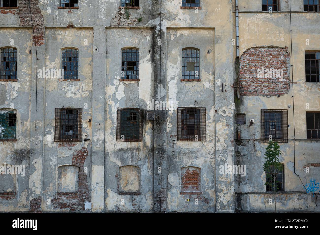 Dilapidated building facade. Cracked and pealed exterior plaster on brick wall and old window ...