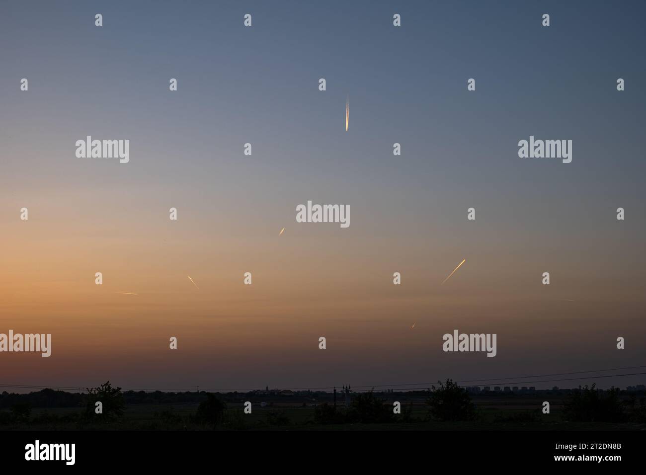 Multiple airplane jet streams in the dusk sky. Wide angle, sunset light ...