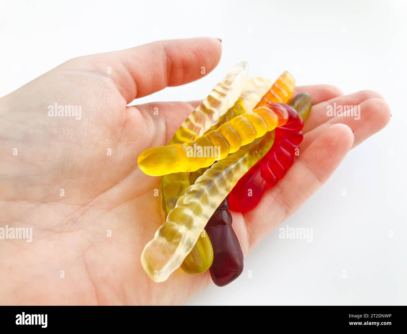 a lot of gummy worms lie on the girl's hand. bright, red, glossy ...