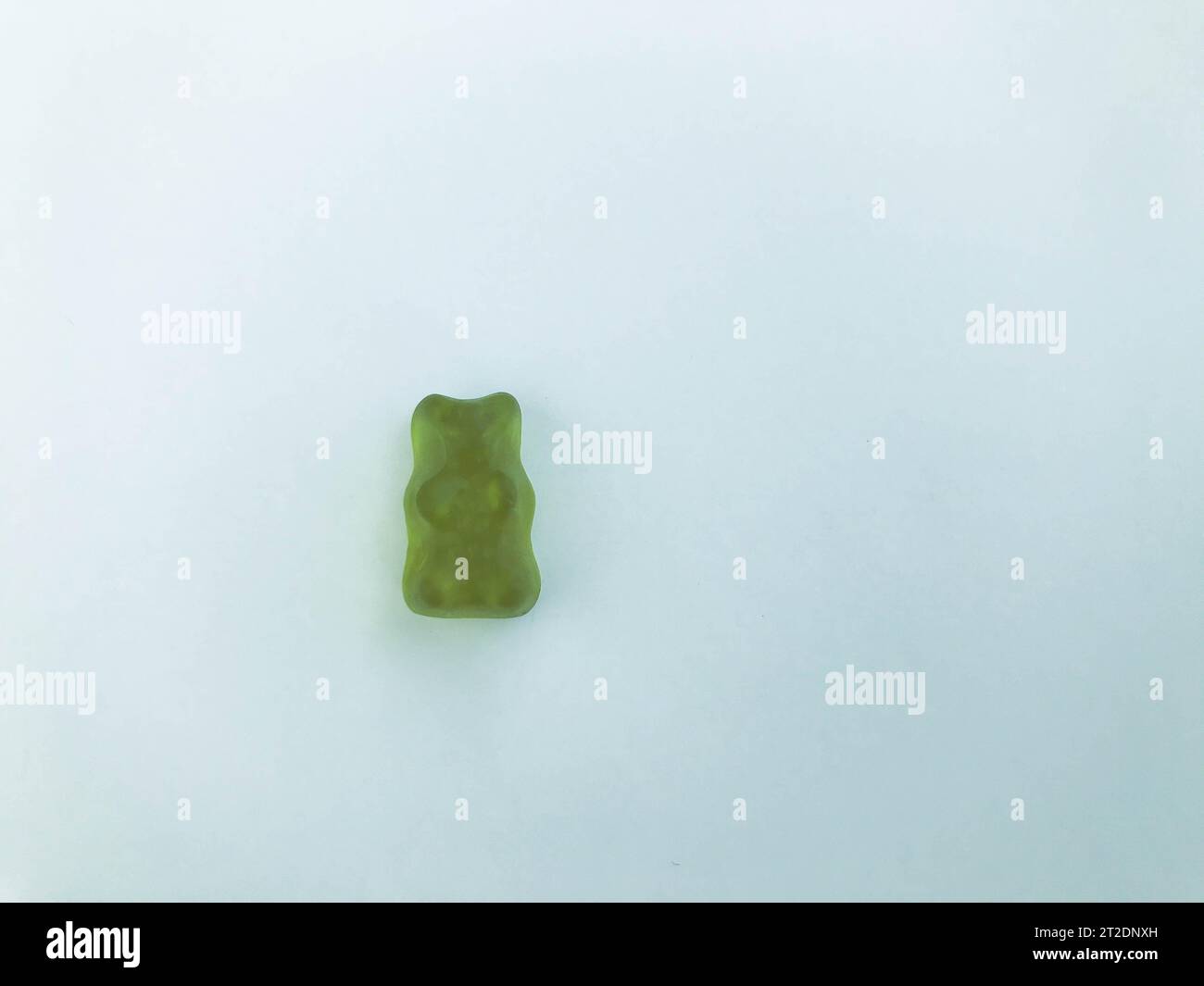 green gelatinous bear on a matte white background. gummy figurine in ...