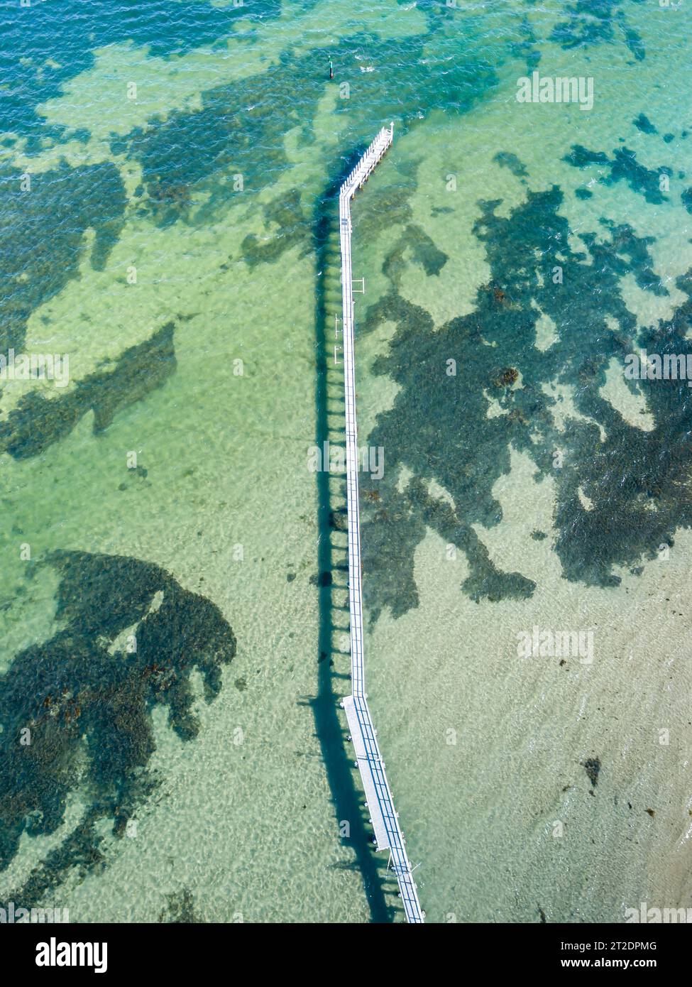Aerial view of a long narrow jetty out over a a shallow coastal bay ...