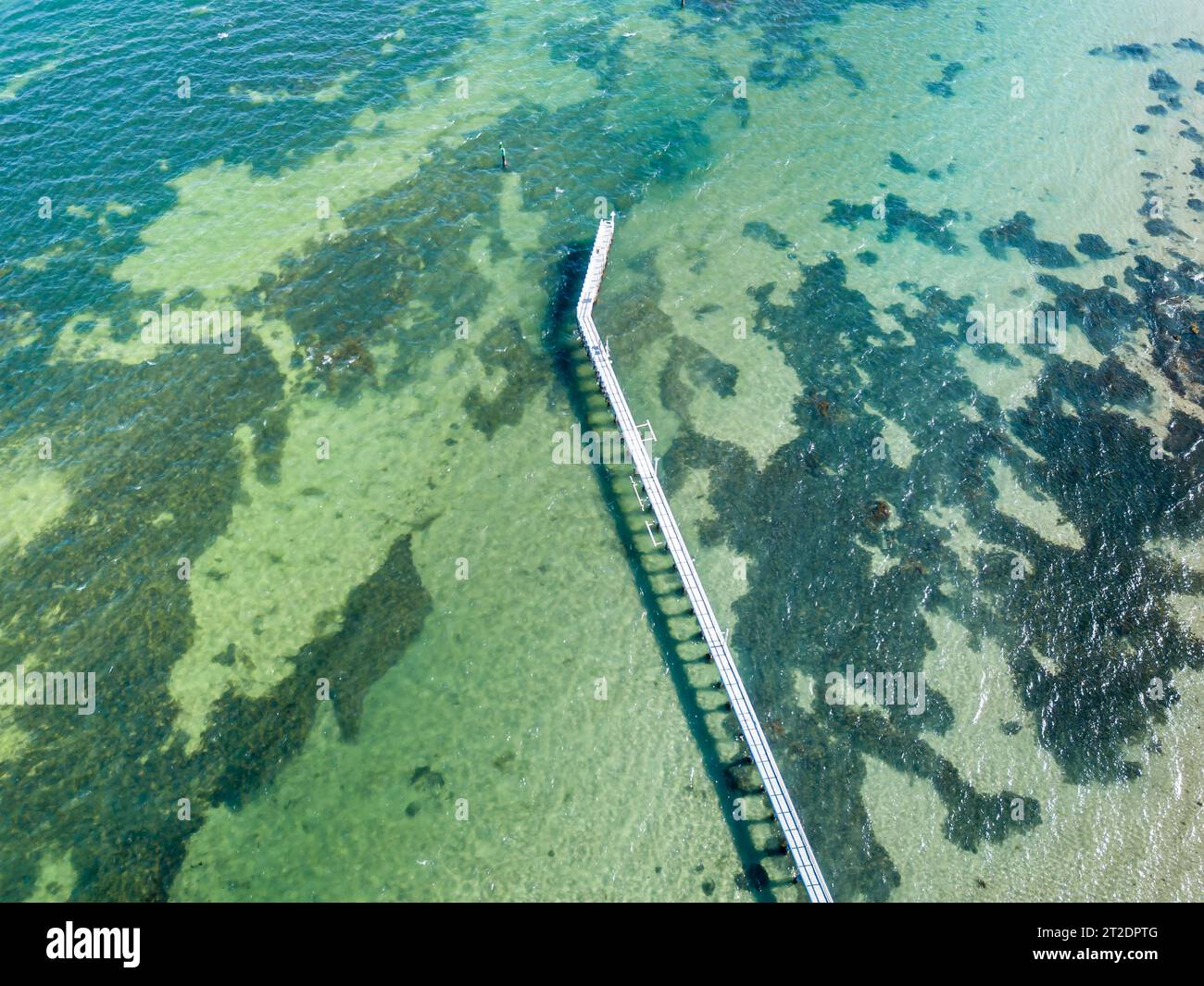 Aerial view of a long narrow jetty out over a a shallow coastal bay ...