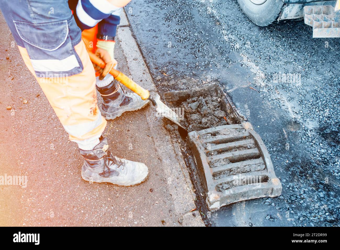 Builder cleaning blocked road gully with shovel and vacuum excavator ...