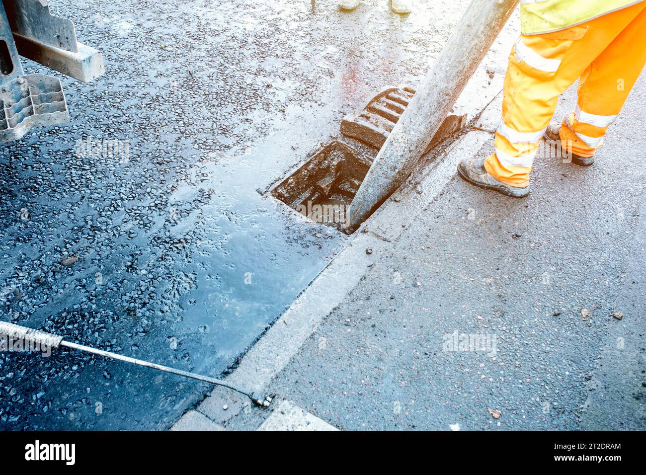 Builder cleaning blocked road gully with shovel and vacuum excavator ...