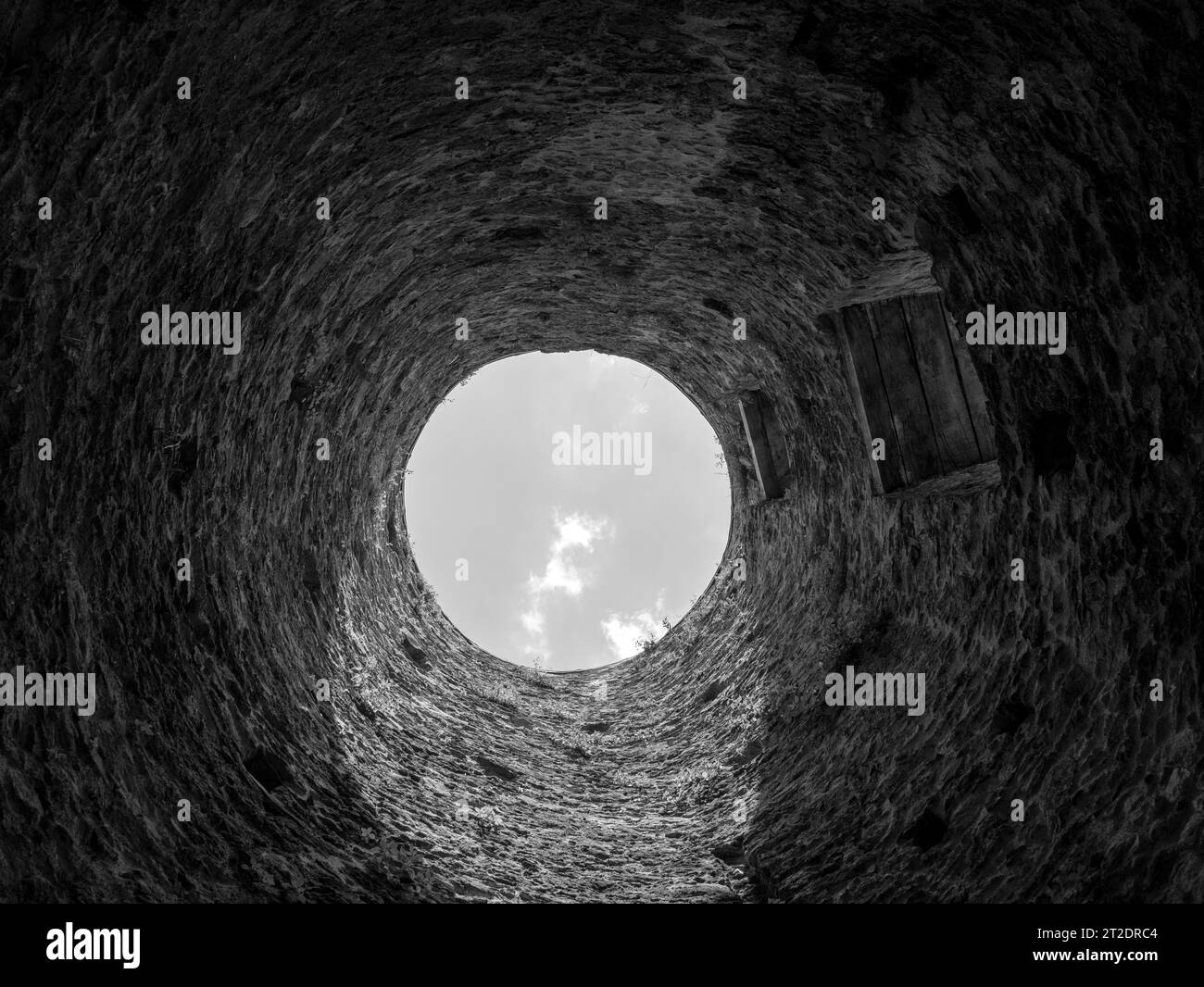 Stone well hole, old construction from inside, brick walls and blue sky ...