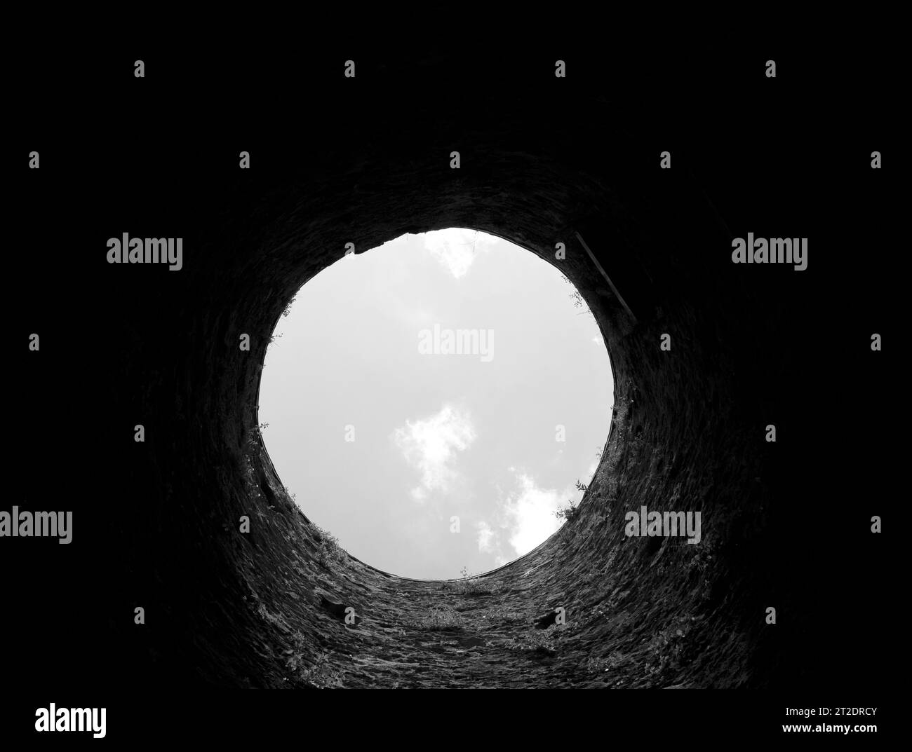 Stone well hole, old construction from inside, brick walls and blue sky ...