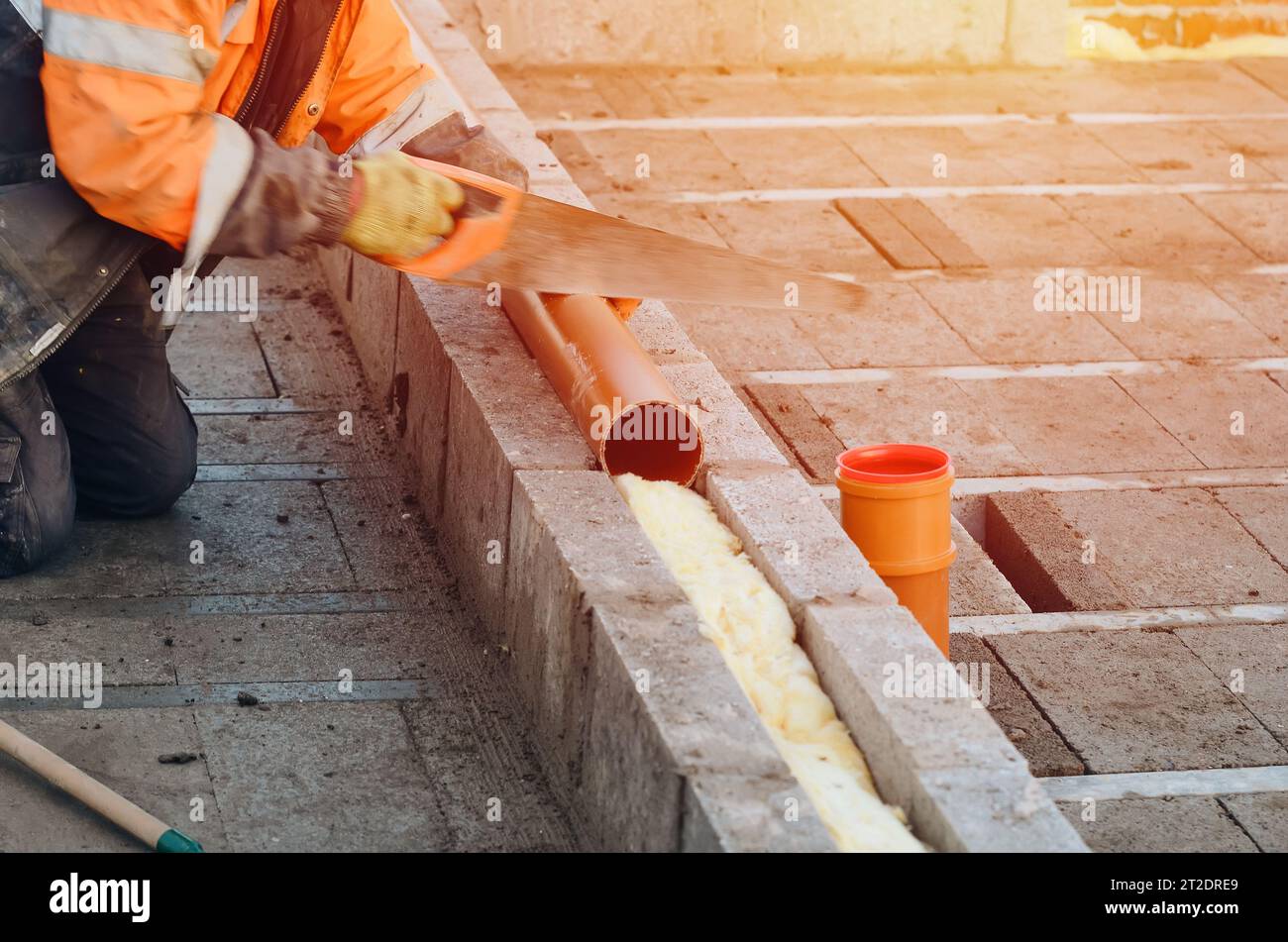 Builder cutting plastic pipe with hand saw during new house internal ...