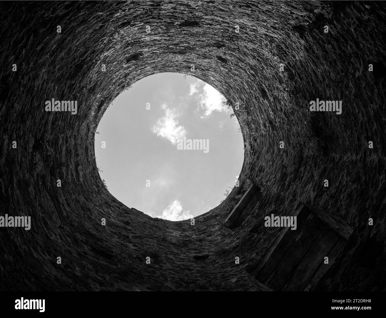 Stone well hole, old construction from inside, brick walls and blue sky ...