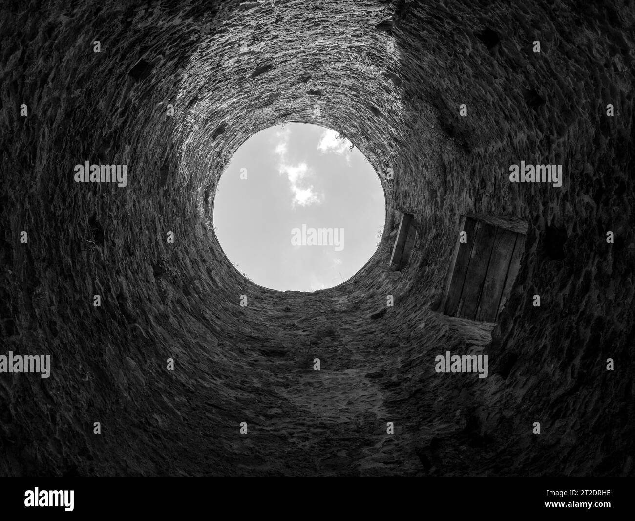 Stone well hole, old construction from inside, brick walls and blue sky ...
