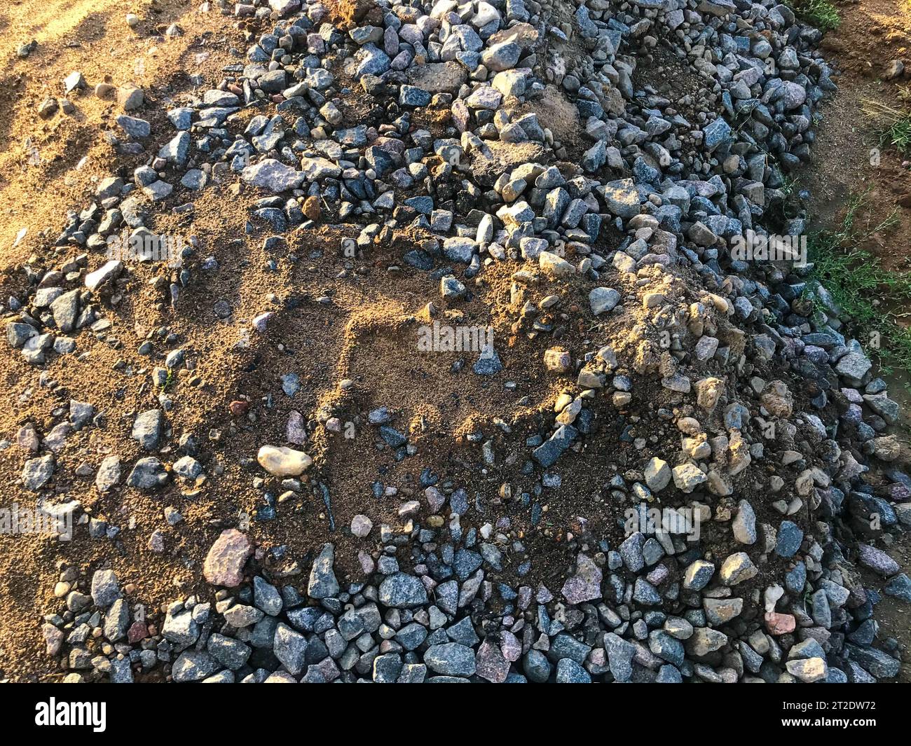stones lie on the ground in black soil. many large stones are piled up ...