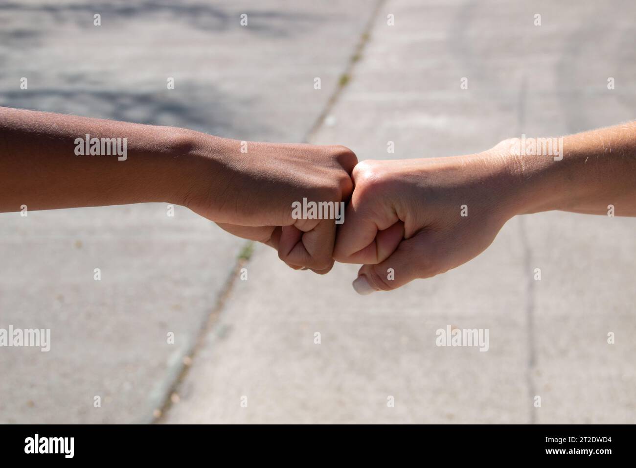 Hands of different ethnicities, African and European, bumping fist to ...