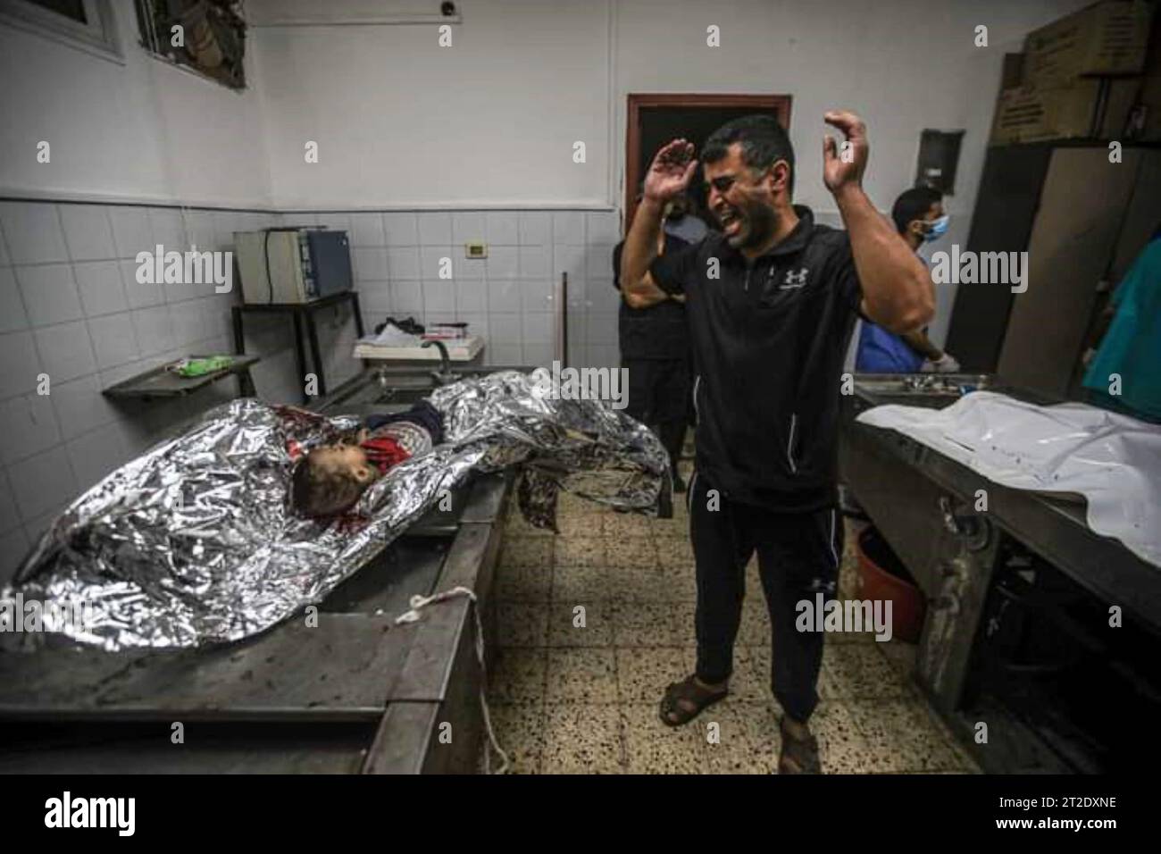 A man moves the body of a Palestinian child inside a morgue in Al-Shifa ...