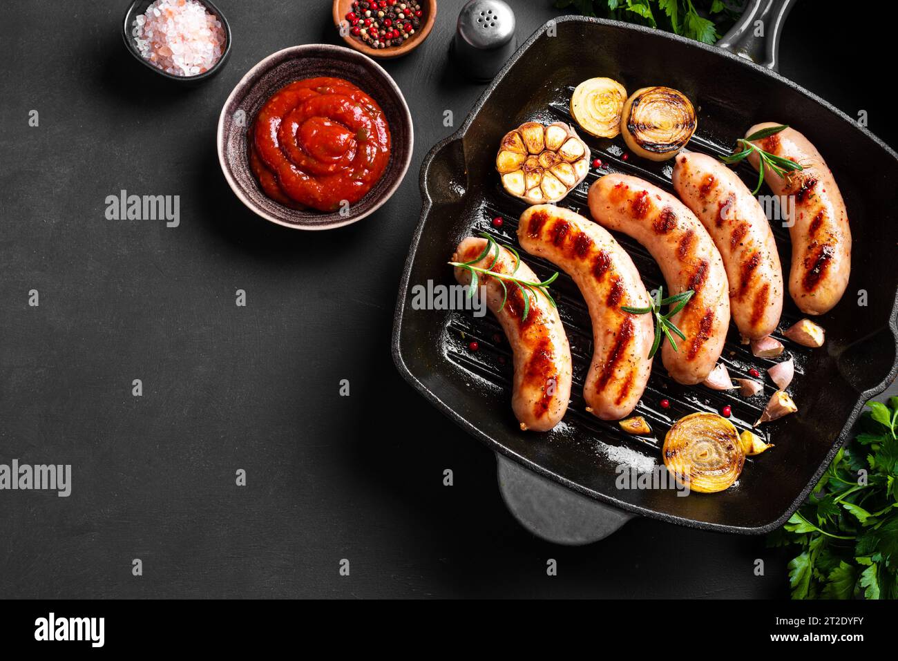 Grilled sausages with vegetables and rosemary on black grill cast iron ...