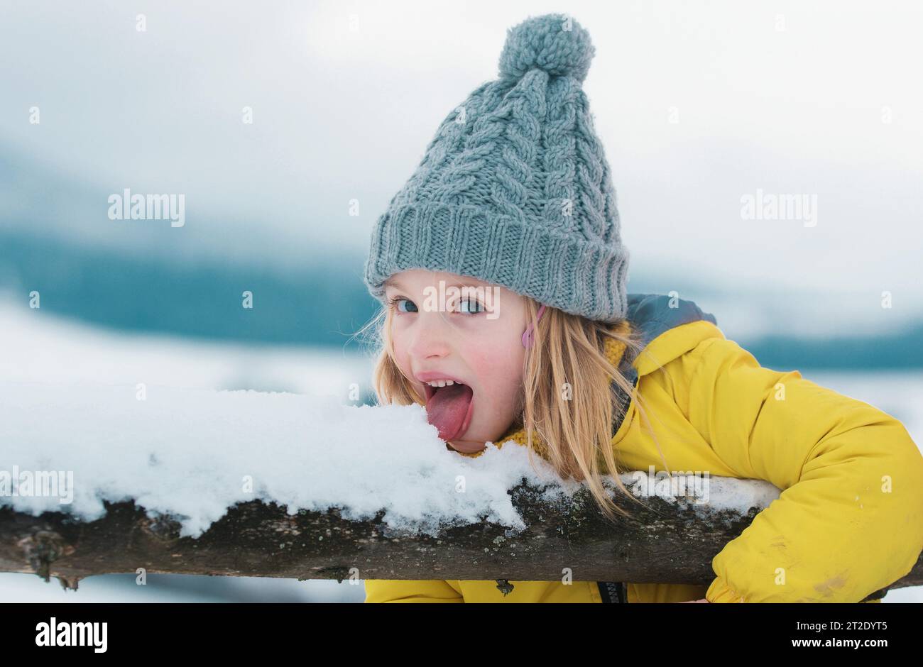Winter girl eating snow outdoor. Funny christmas kids holiday. Kids ...