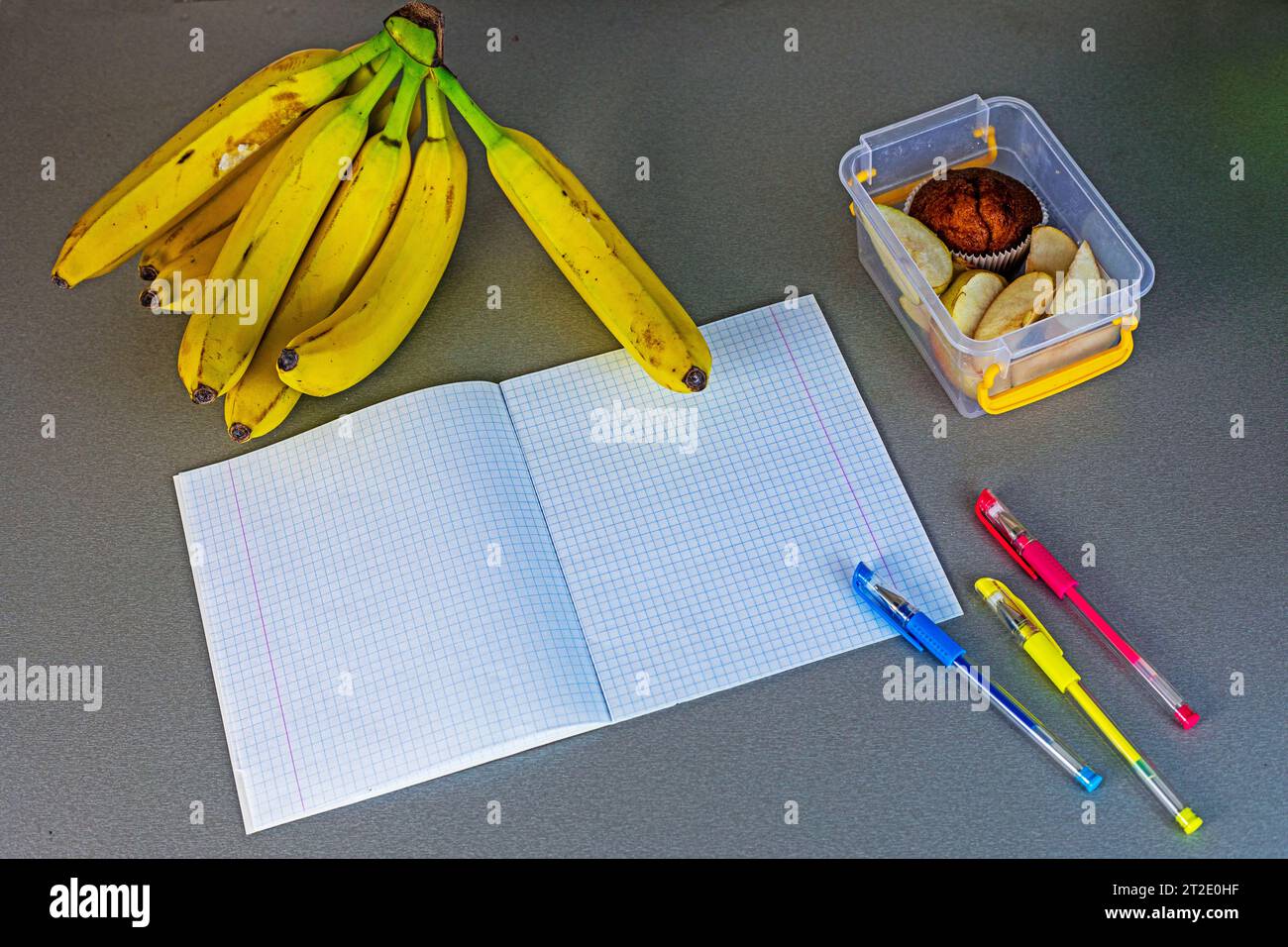 bunch of bananas on the kitchen table next to a container with apple ...