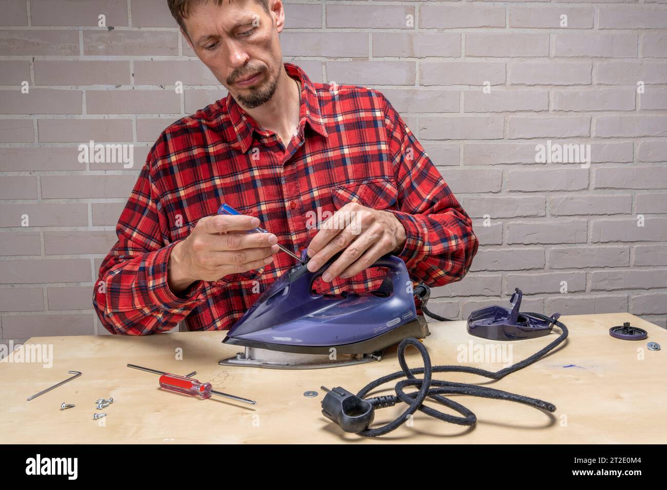 the ironing iron is broken. the master repairs the iron in the workshop ...