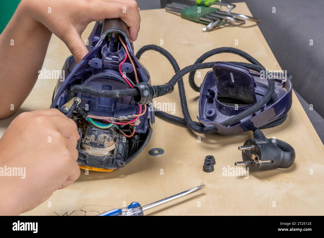 Disassembled electric iron. repairman checking and fixing broken iron ...