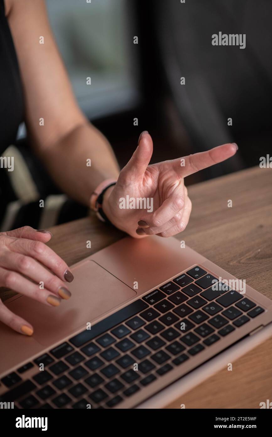 Close-up of a hand gesturing above a modern laptop keyboard ...