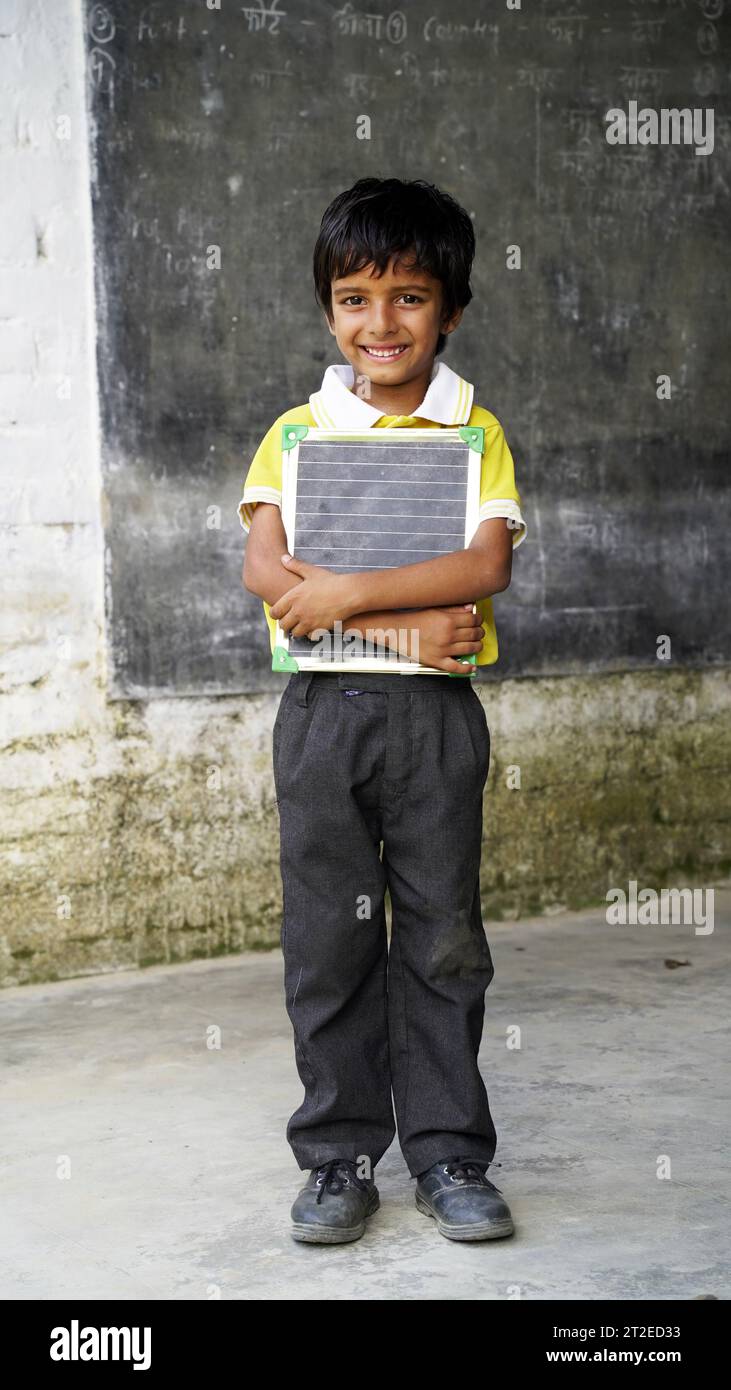 Indian school boy standing against blank chalkboard, intelligent and ...
