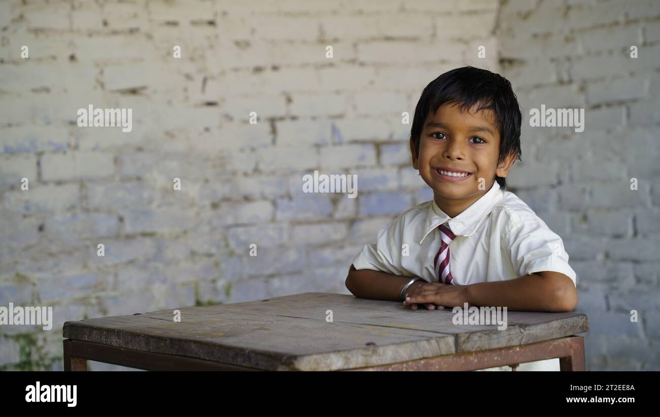 Portrait of happy indian school child sitting at desk in classroom ...