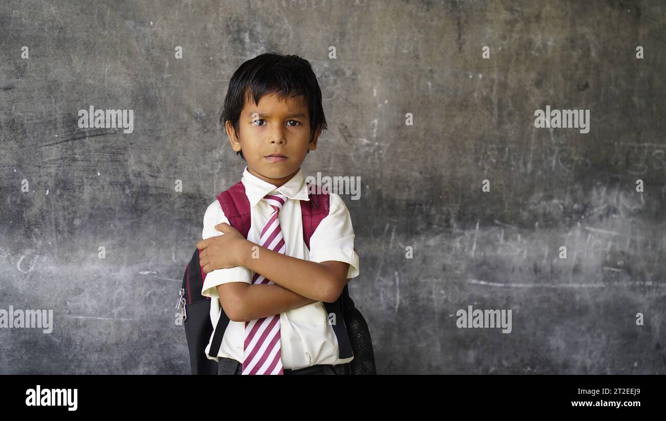 Indian school boy standing against blank chalkboard, intelligent and ...