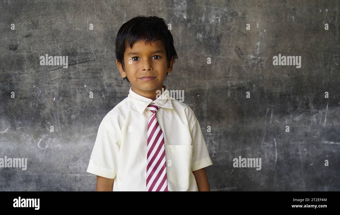 Indian school boy standing against blank chalkboard, intelligent and ...
