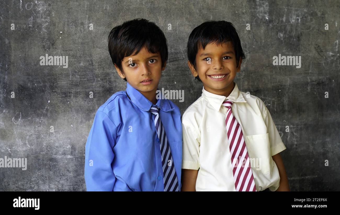 Indian school boy standing against blank chalkboard, intelligent and ...