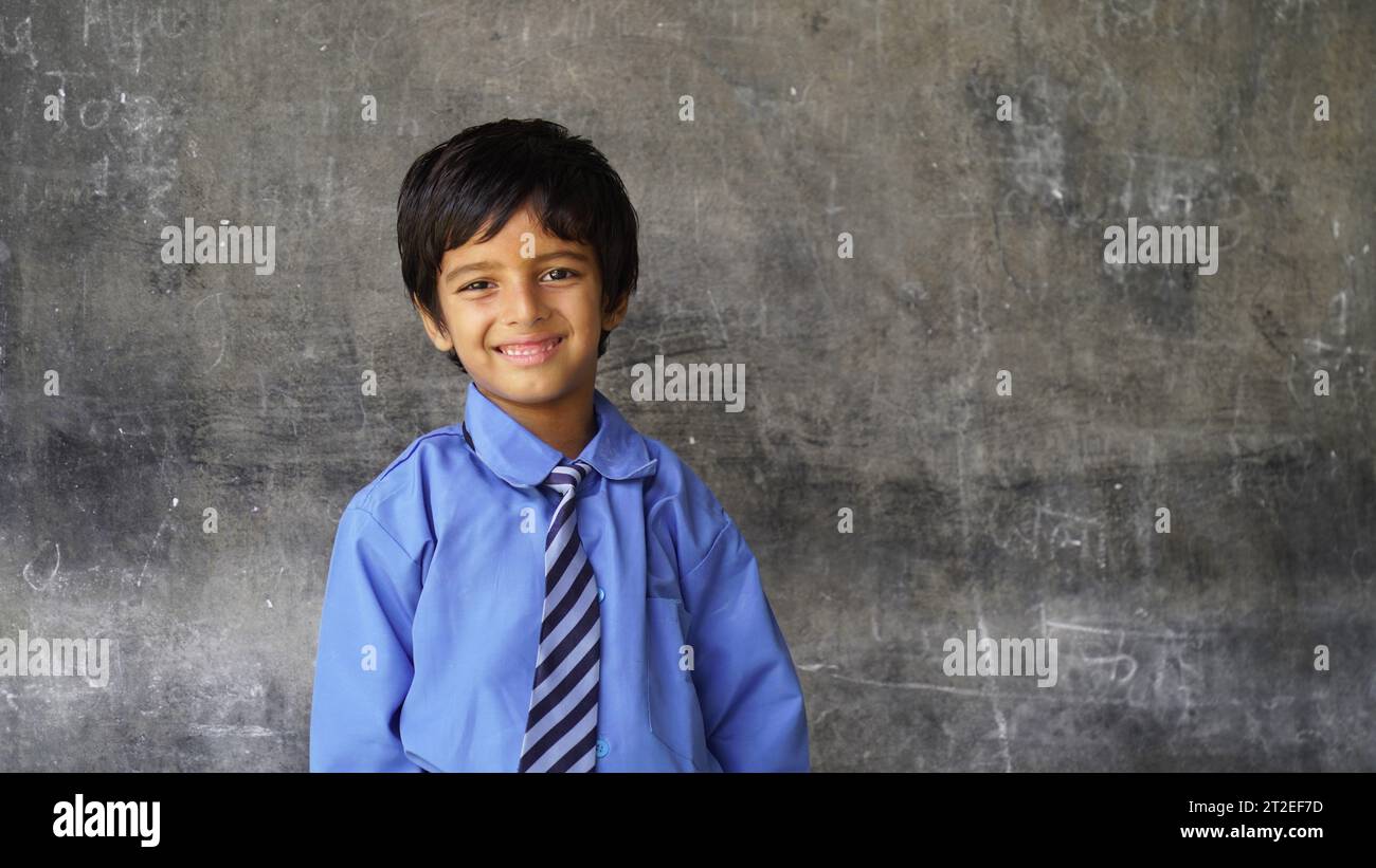 Indian school boy standing against blank chalkboard, intelligent and ...