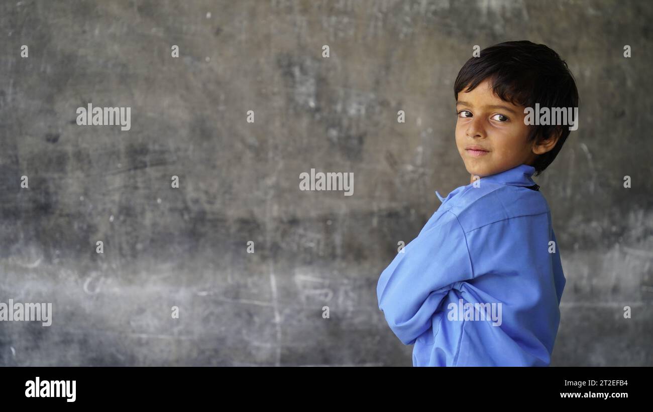 Indian school boy standing against blank chalkboard, intelligent and ...