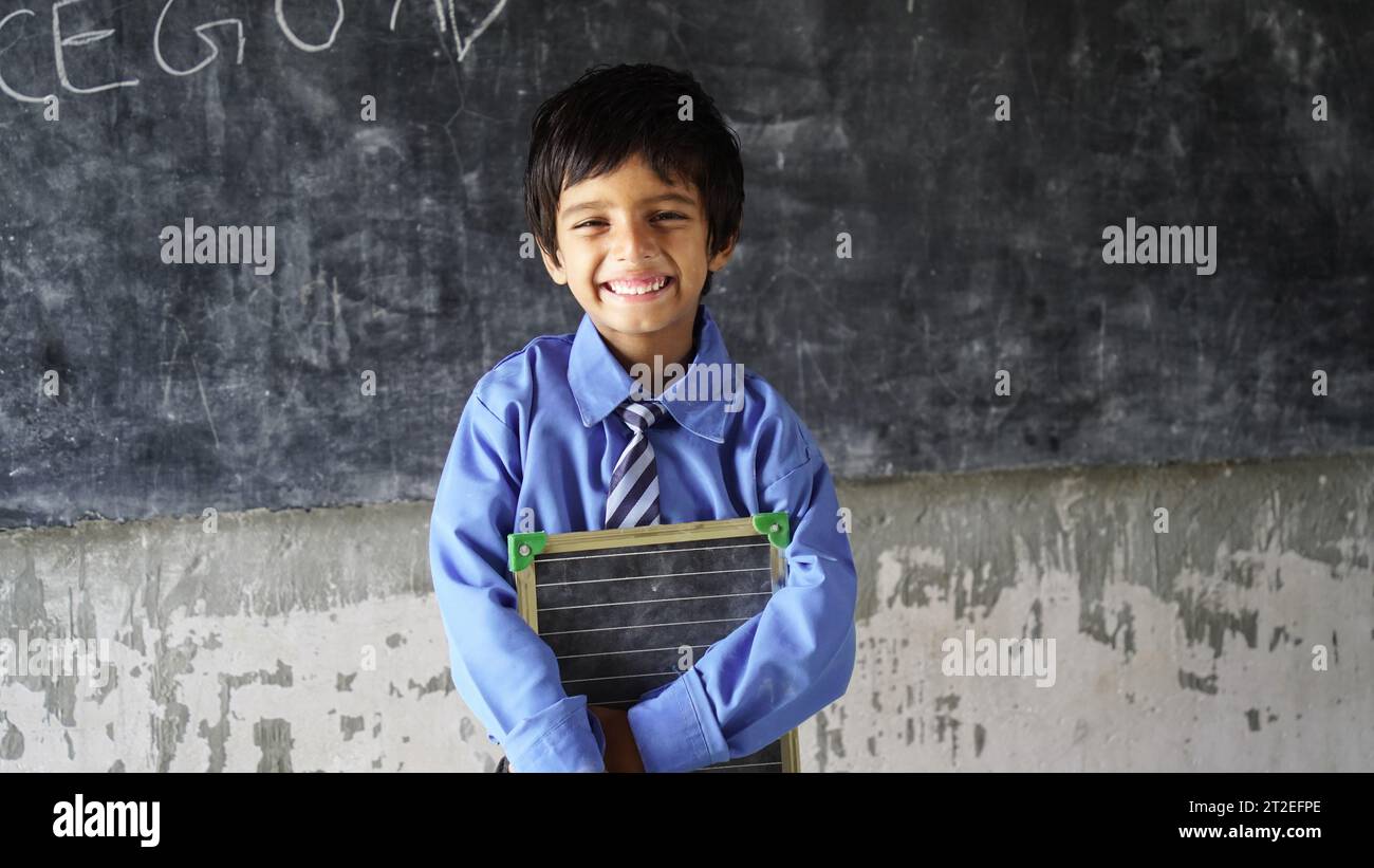 Portrait of happy indian school child sitting at desk in classroom ...