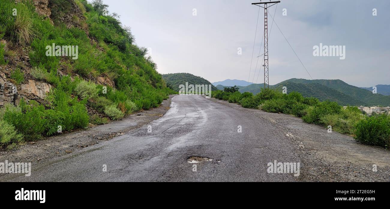 A scenic shot of a road winding alongside a steep and rocky cliff face ...