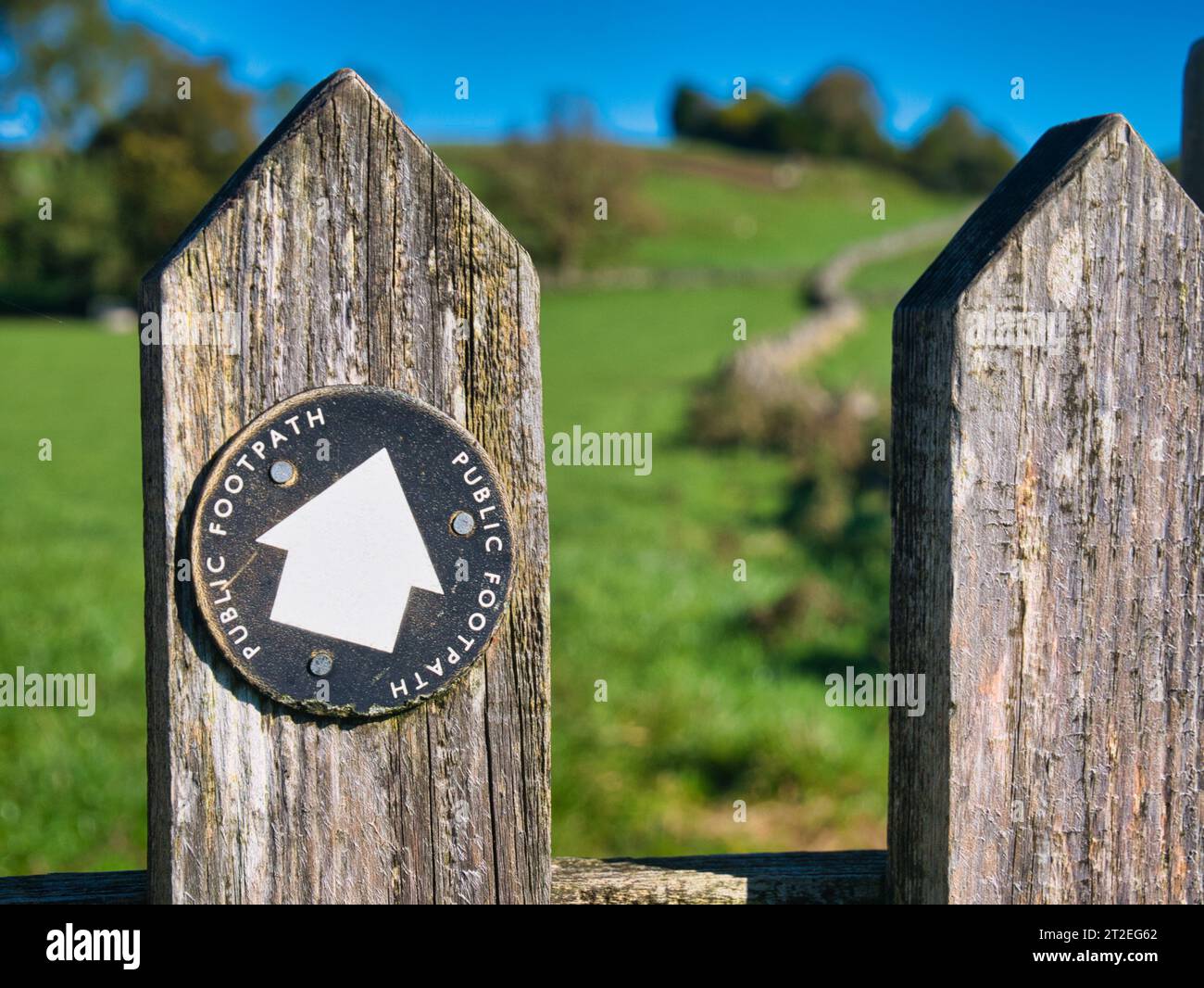 A black and white way marker on a weathered wooden gate points the way ...
