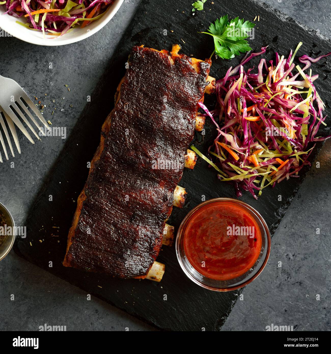 Spicy grilled spare ribs on black board over dark stone background. Top ...