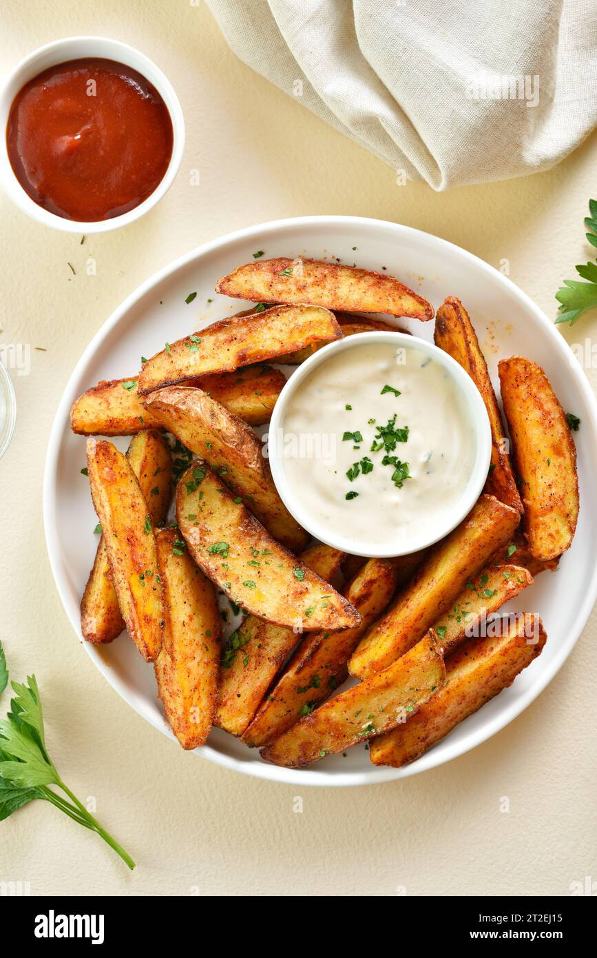 Oven baked potato wedges with sauce over light stone background. Top ...