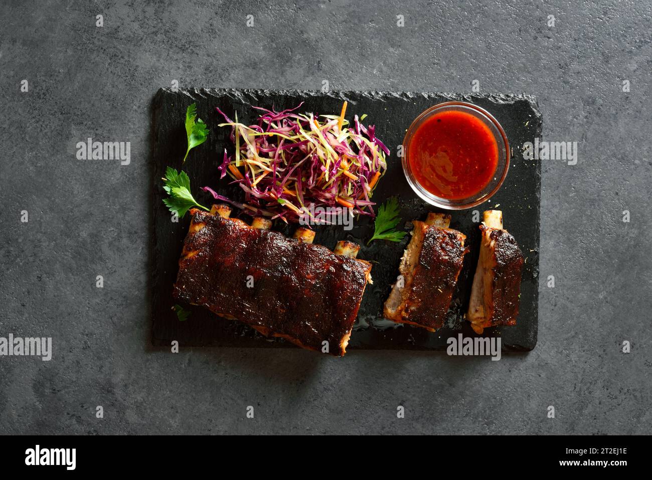 Grilled spare ribs on black board over dark stone background. Top view ...