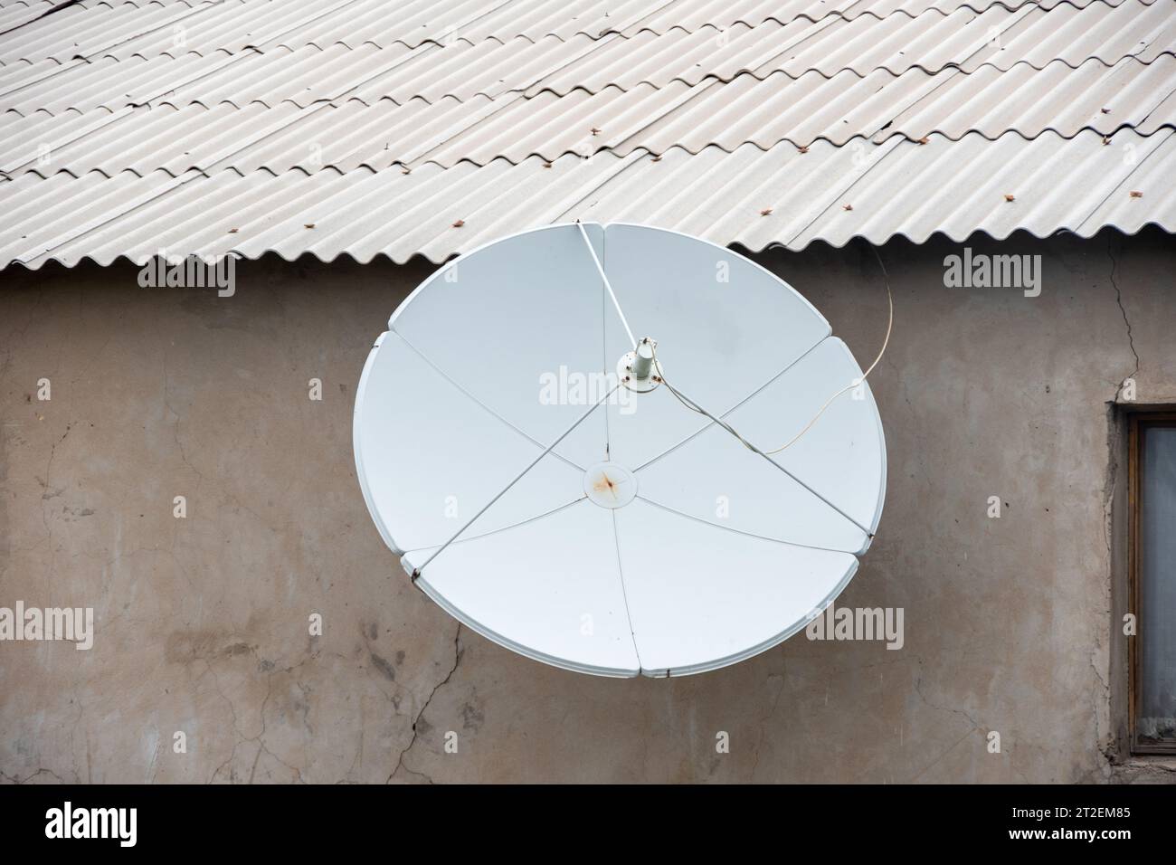 Satellite TV antenna on the wall of the house. Round white antenna receiver for radio signal ...