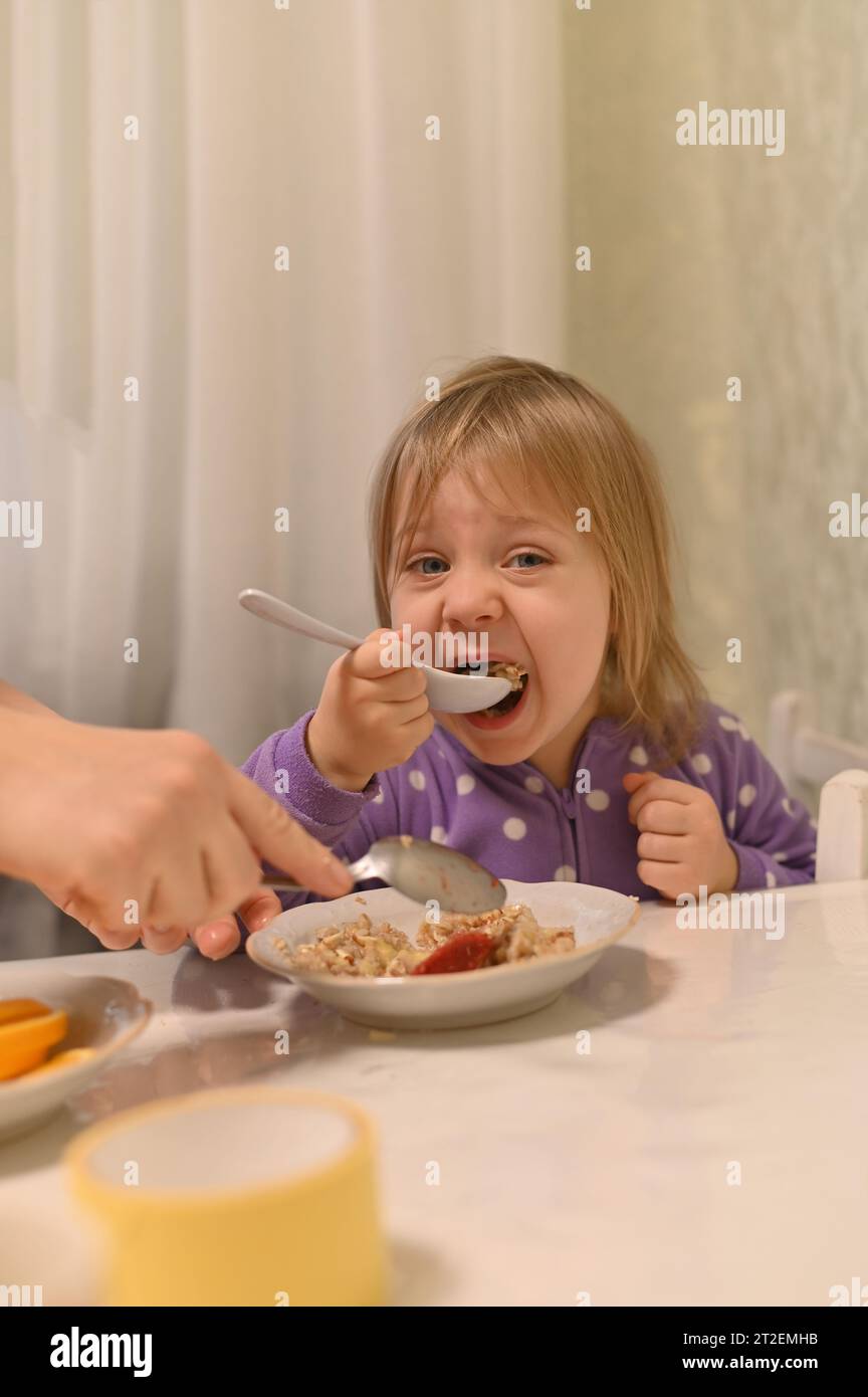 little girl eats with great appetite. a big spoon in her hands Stock ...