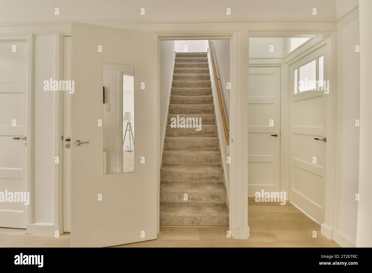 an empty room with stairs leading up to the second floor and two doors ...