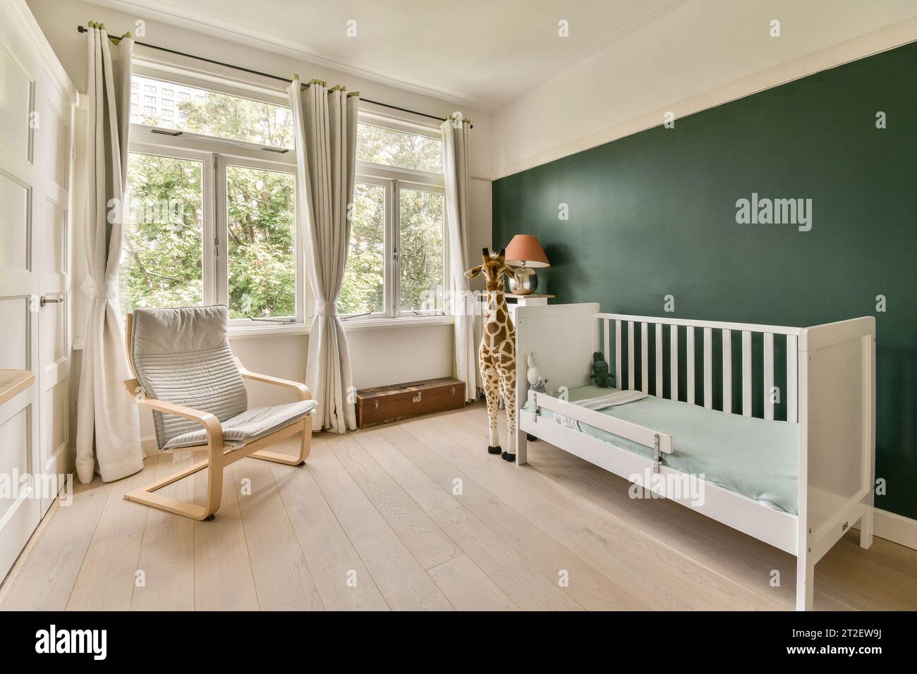 a baby's room with a cribt and a rocking chair in front of the window ...
