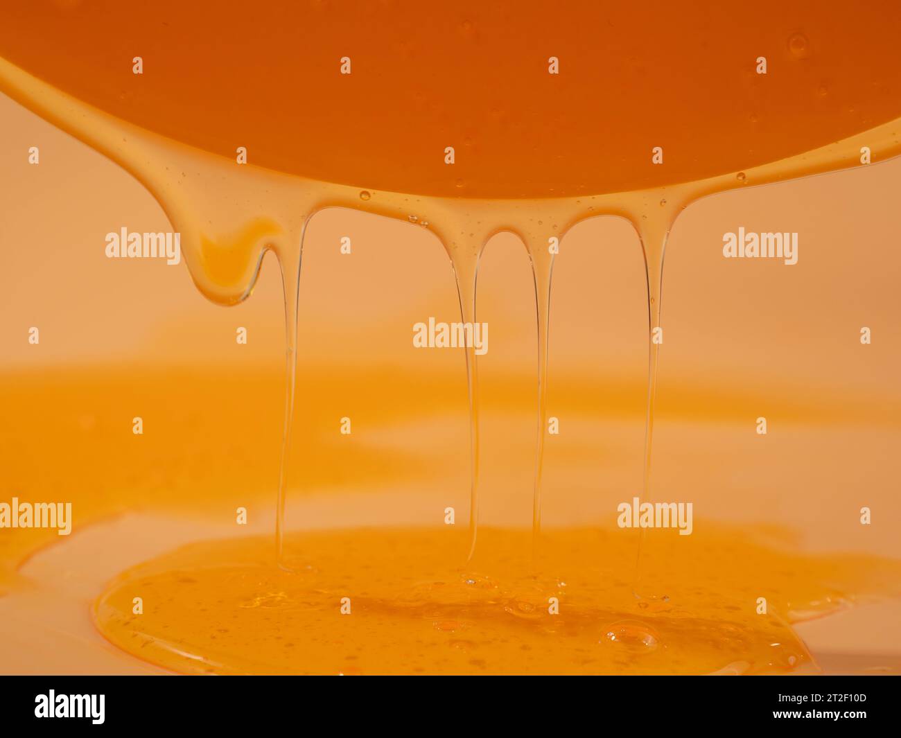 Liquid shower gel flows gracefully across a bright orange background ...