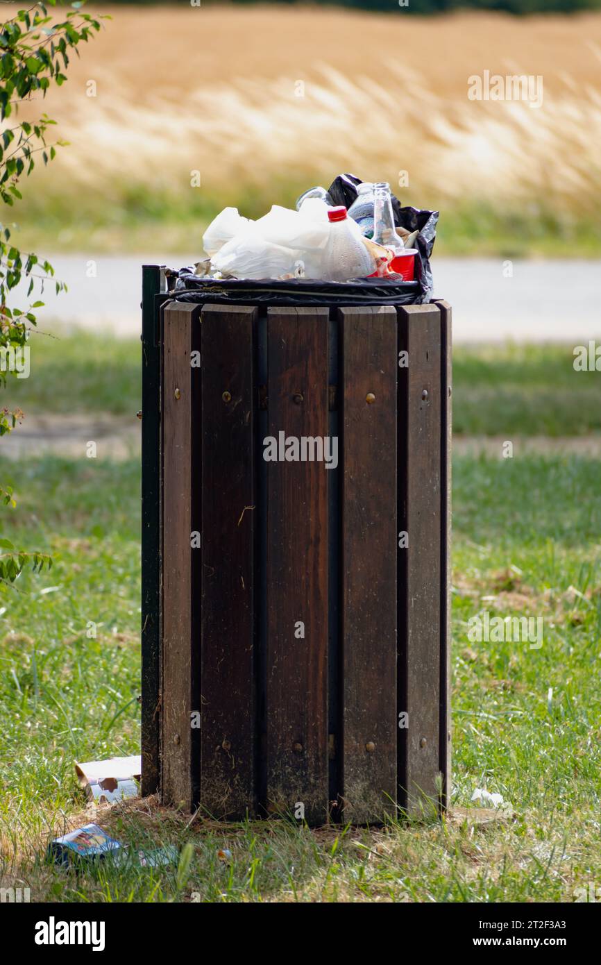 Public trash can in a park filled with overflowing trash Stock Photo ...