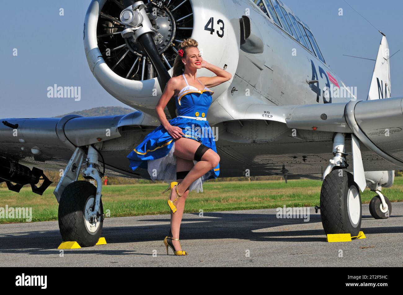 Navy dressed pin-up girl standing in front of an SNJ trainer aircraft ...