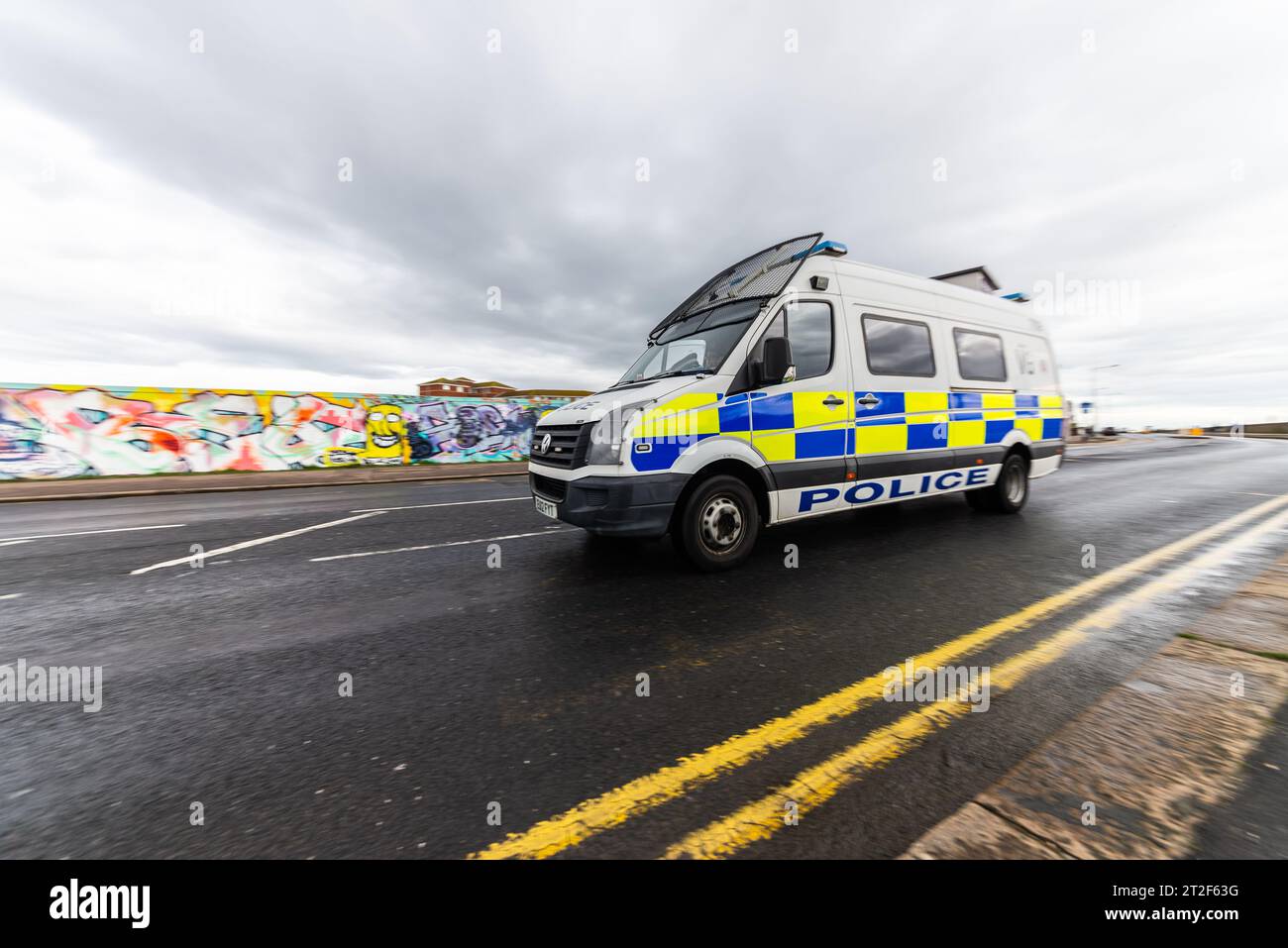 Police van passing graffiti covered hoarding on Southend on Sea ...