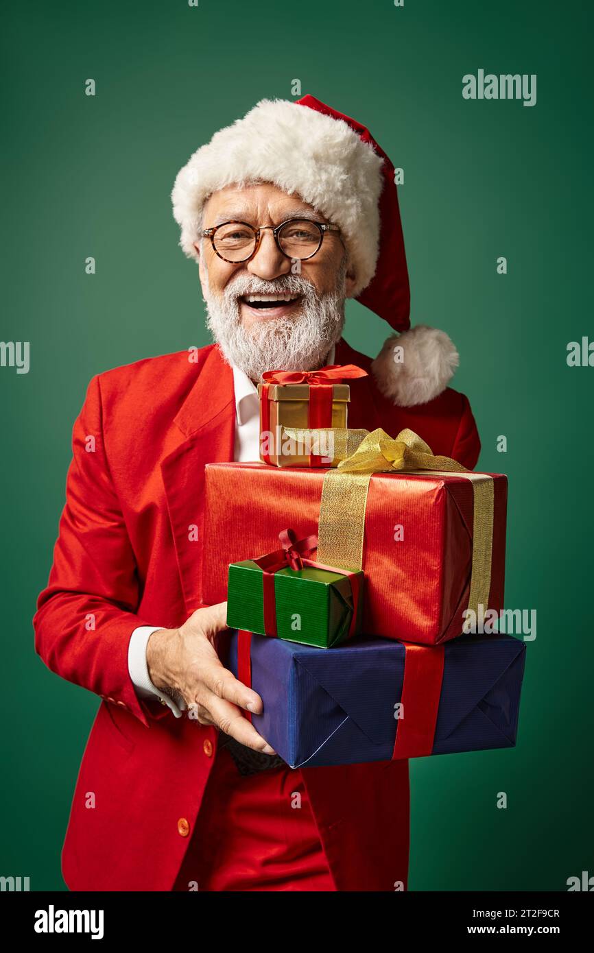 portrait of elegant Santa in red attire holding bunch of presents ...